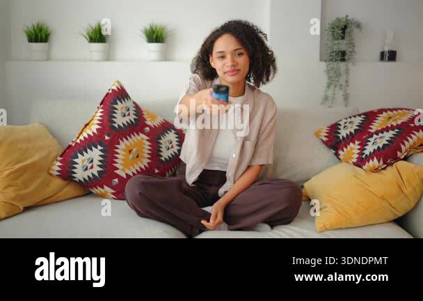 Woman using a TV remote control while Concerned looking at a screen ...