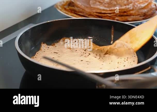 Thin crepe is turned over in hot skillet using wooden spatula. Steam ...
