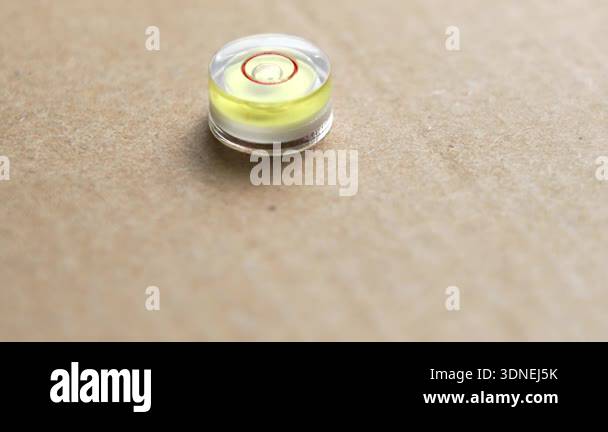 Round bubble level on a brown flat surface. Precision measurement tool ...