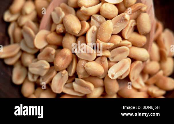 Top view of a pile of salted roasted peanuts inside a wooden bowl with ...