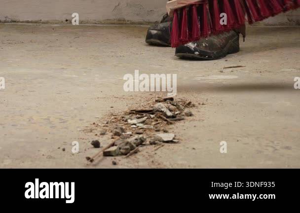 Broom sweeping debris away from camera on concrete floor during ...
