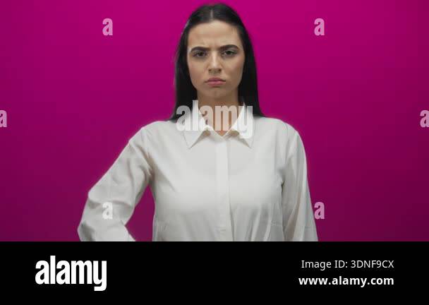 Woman with hand over face in front of vibrant pink wall, expressing ...