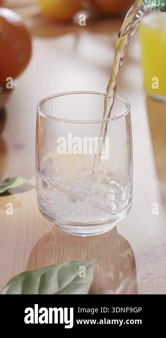 Fizzy water is poured into a glass from a plastic bottle close up ...