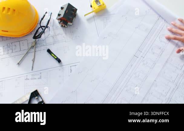 Top view male hands laying out blueprints on the white table lit by the ...