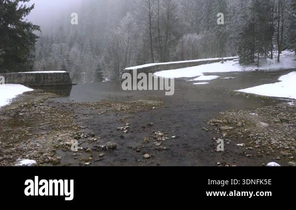 Shallow river crossing with stone embankments surrounded by misty ...