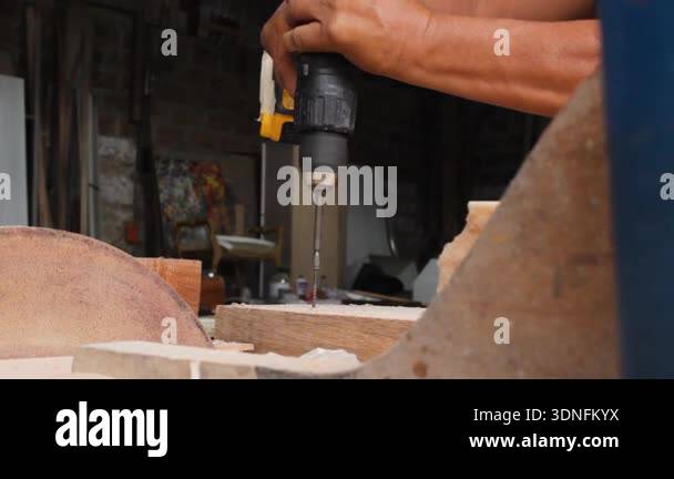 An unrecognizable man is drilling a wooden board with a cordless ...