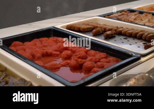 Close up of hot buffet dishes with sausages and meatballs in sauce ...