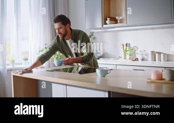 Man cleaning kitchen countertop enjoying daily housekeeping routine ...