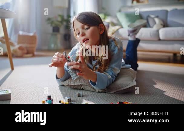 Playful girl building lego on carpet living room closeup. Focused ...