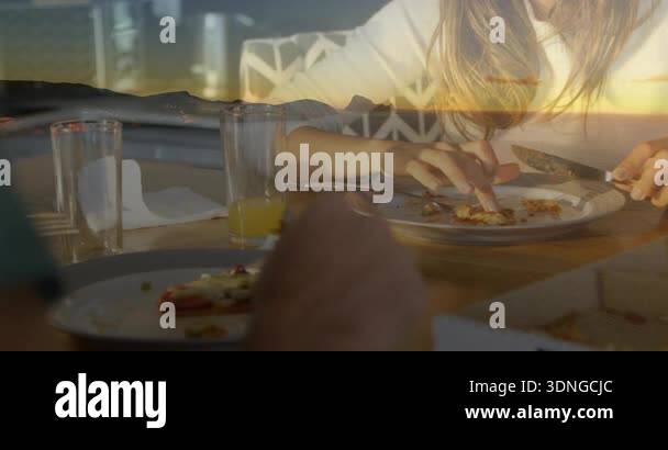 Couple after eating pizza reaching across restaurant table as sunset ...