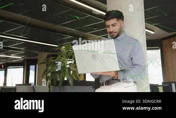 Leaning against column in office, man analyzing laptop data sparking ...