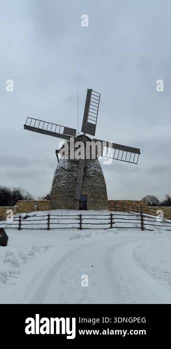 Historic stone windmill with wooden blades in a snow-covered rural ...