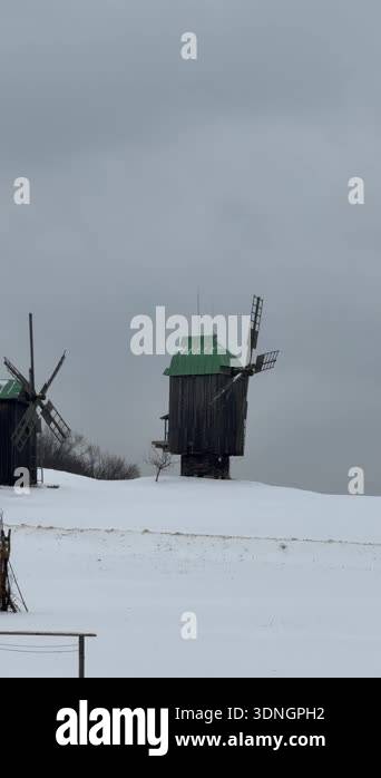 Traditional wooden windmills with green roofs in a snow-covered rural ...