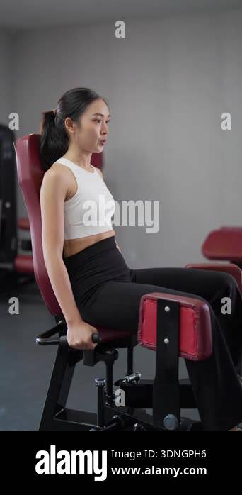 A determined and strong Asian woman is lifting weights at a fitness ...