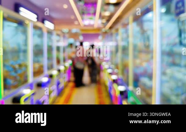 Blurred background of a crowded arcade featuring vibrant claw machines ...