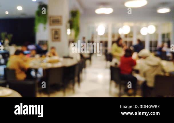 Busy restaurant scene featuring blurred of people eating with family ...