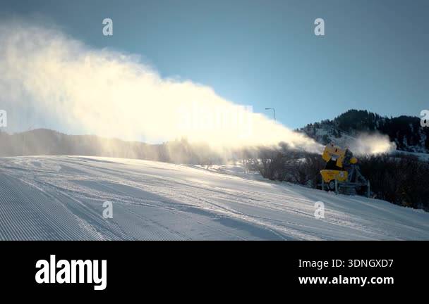 Yellow snowmaking machine producing artificial snow at mountain ski ...