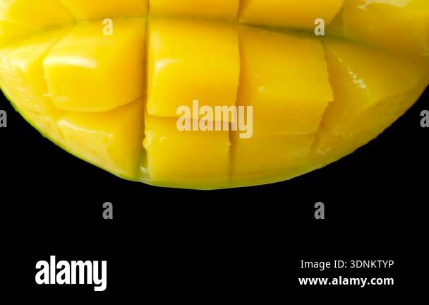 Mango juice slowly dripping from fresh fruit, black background, macro ...