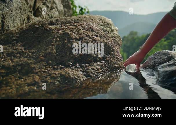 Close-up of middle-aged woman hand collecting clean spring water into ...