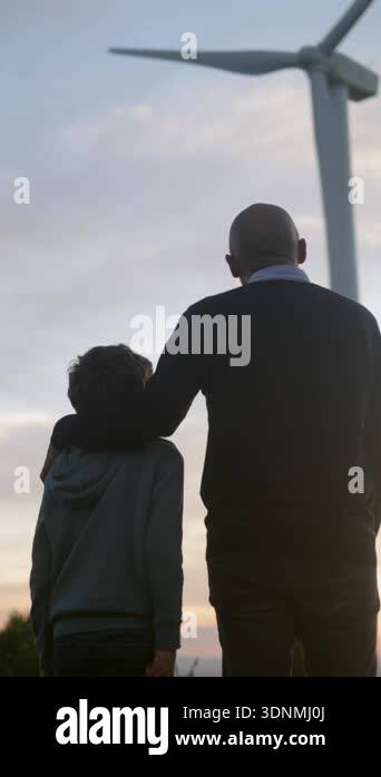 father spending time outdoors together with son at sunset near wind ...