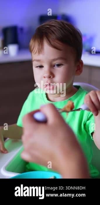 Little cute baby boy dances sitting in high chair. Mom takes her son's ...