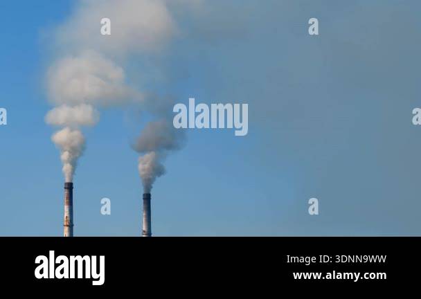 Smoke rises from factory chimneys during daylight in urban area. Two ...