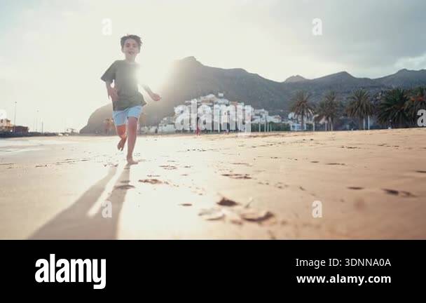 Happy boy running toward the camera on sandy ocean beach. Smiling child ...