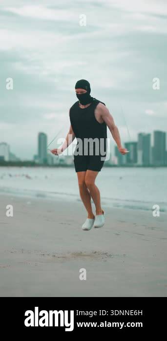 Man bodybuilder jumping rope at sea beach during sunset workout on city ...