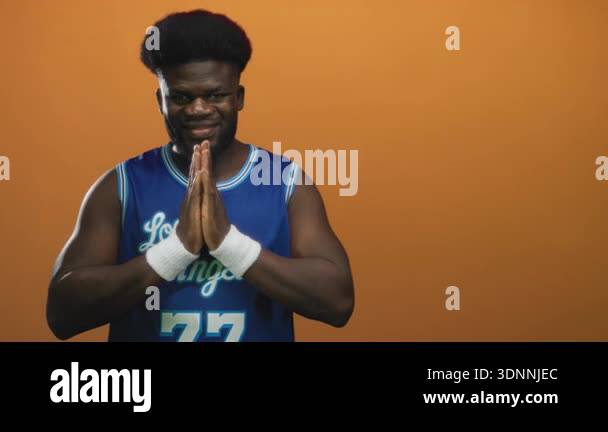 Man with hands pressed together in praying gesture wearing blue los ...