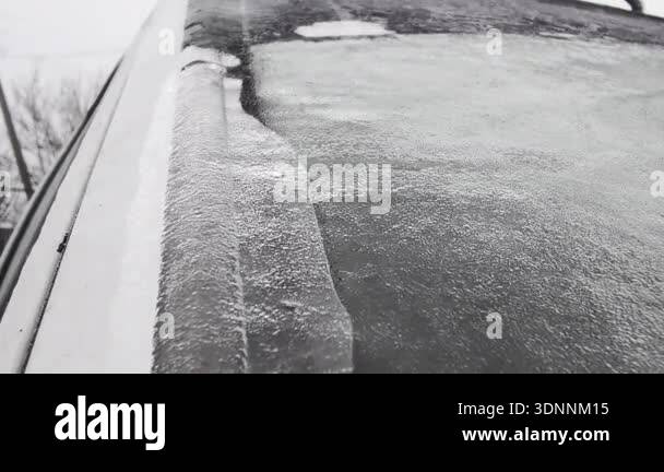 Icy car windshield covered with ice, peeling edge along roof, thick ...