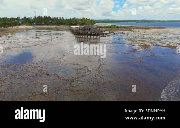 Aerial view of a wooden pier and building extending over a shallow reef ...