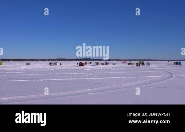 Aerial flying view of the frozen Simcoe lake showing the snowmobile ...