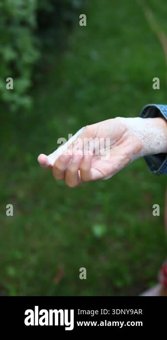 Hand is rubbing together with soap bubbles while standing outdoors in a ...