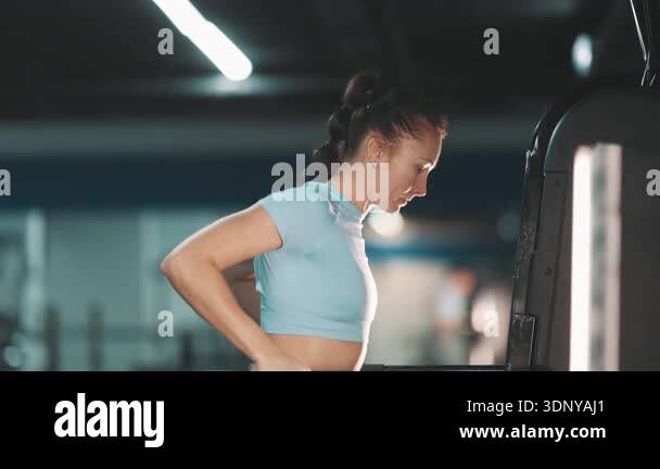 Strong woman performing triceps dips exercise on a parallel bar machine ...