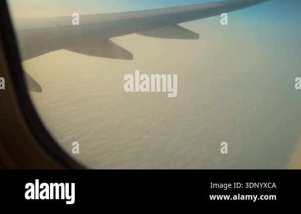 Plane flying above dense clouds at sunset, view from window porthole ...
