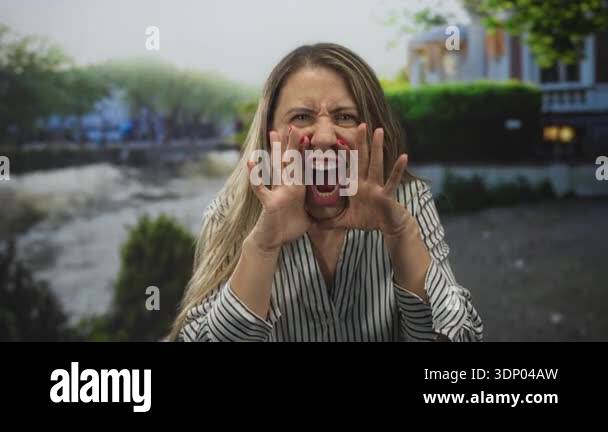 Woman cupping hands to mouth shouting on street as canal water flows ...