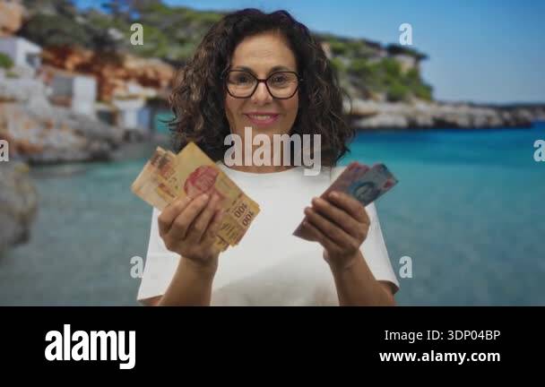 Woman holding mexican pesos at a seaside beach, showcasing currency in ...