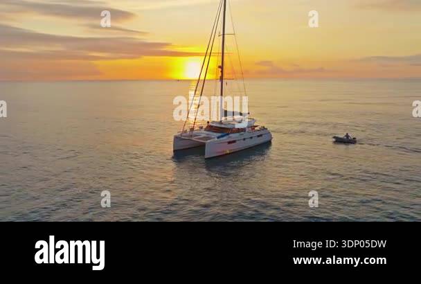Aerial view of catamaran anchored in the calm sea at amazing sunset ...