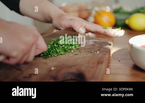 Slow motion closeup of a chefs hands chopping fresh parsley with a ...