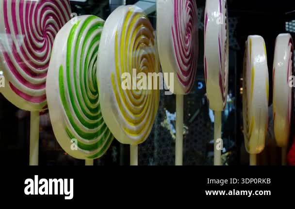 Rows of large colorful spiral lollipops with pink, green, yellow, and ...