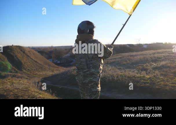 Female military in uniform waving flag of Ukraine at countryside. Young ...