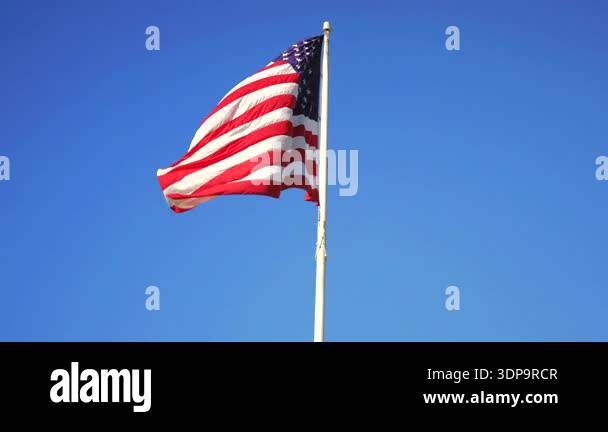 American flag waving on tall pole against clear blue sky, national ...