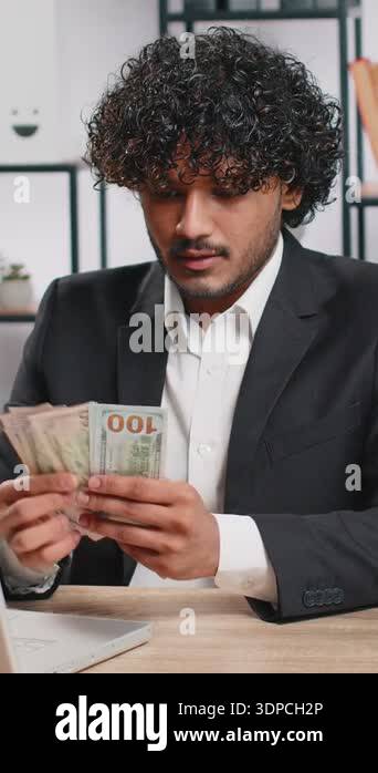 Rich Indian businessman working on laptop pc counting money cash ...