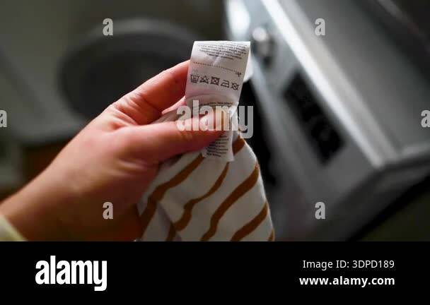 Woman reading clothing label with care symbols and information on ...