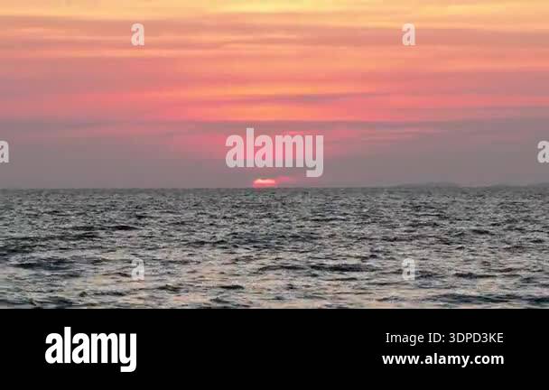 Dramatic and colorful pink sunset disappearing below the ocean horizon ...