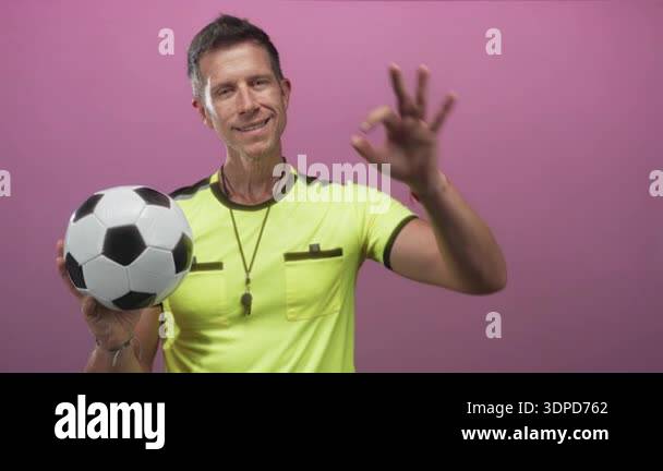 Man referee holding soccer ball and making ok sign while wearing neon ...