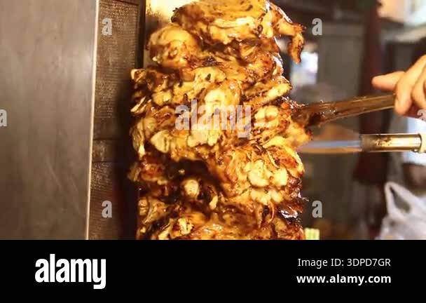 Professional gas torch searing seasoned chicken doner kebab meat at a ...
