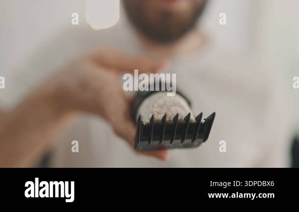 Barber cleaning a professional electric hair clipper after a haircut in ...