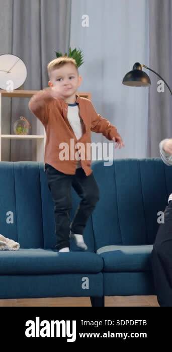 Cute 2-aged boy jumping and dancing on the couch when his eldest ...