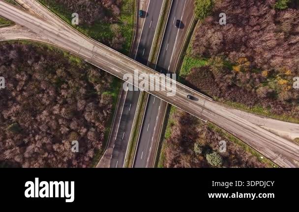 Vehicles move along a highway intersection surrounded by green and ...